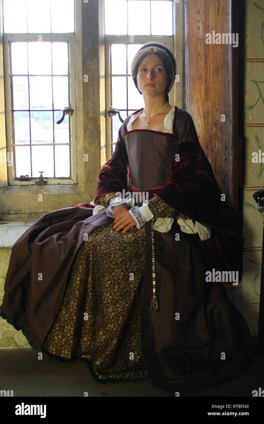 A beautiful young Woman dressed as Anne Boleyn sits by a window at the ...