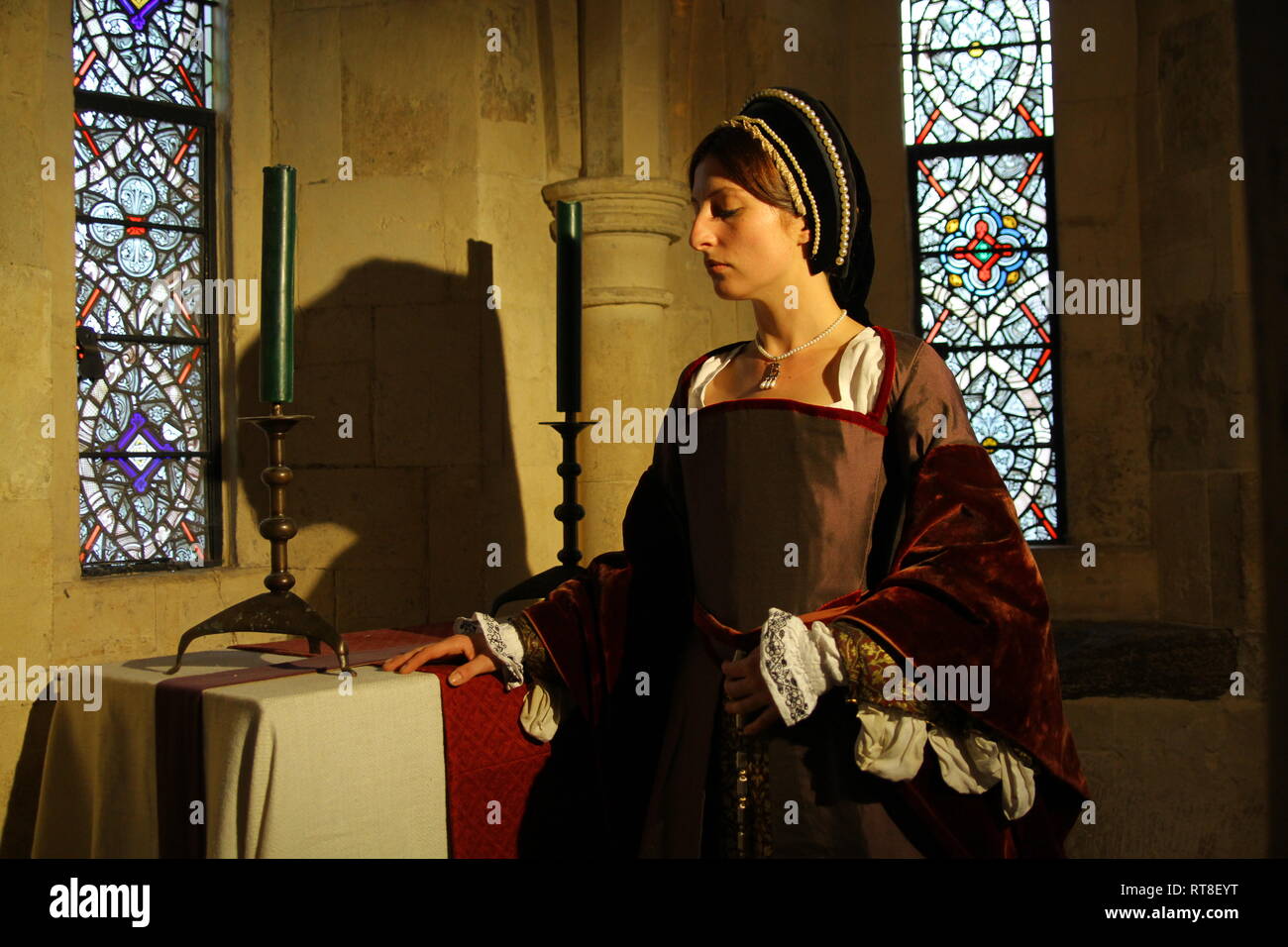 A beautiful young Woman dressed as Anne Boleyn sits by a window at the ...