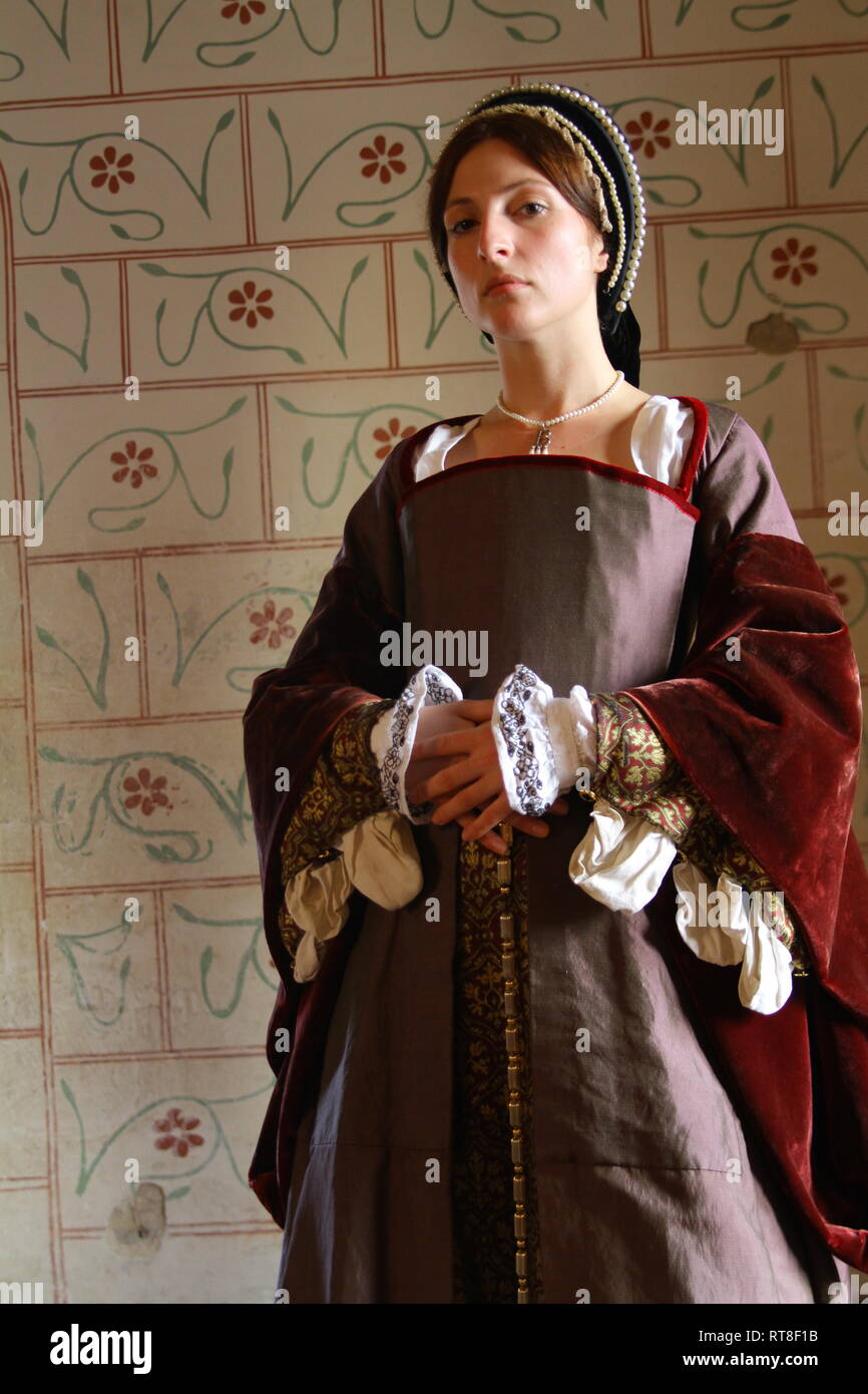 A beautiful young Woman dressed as Anne Boleyn sits by a window at the ...