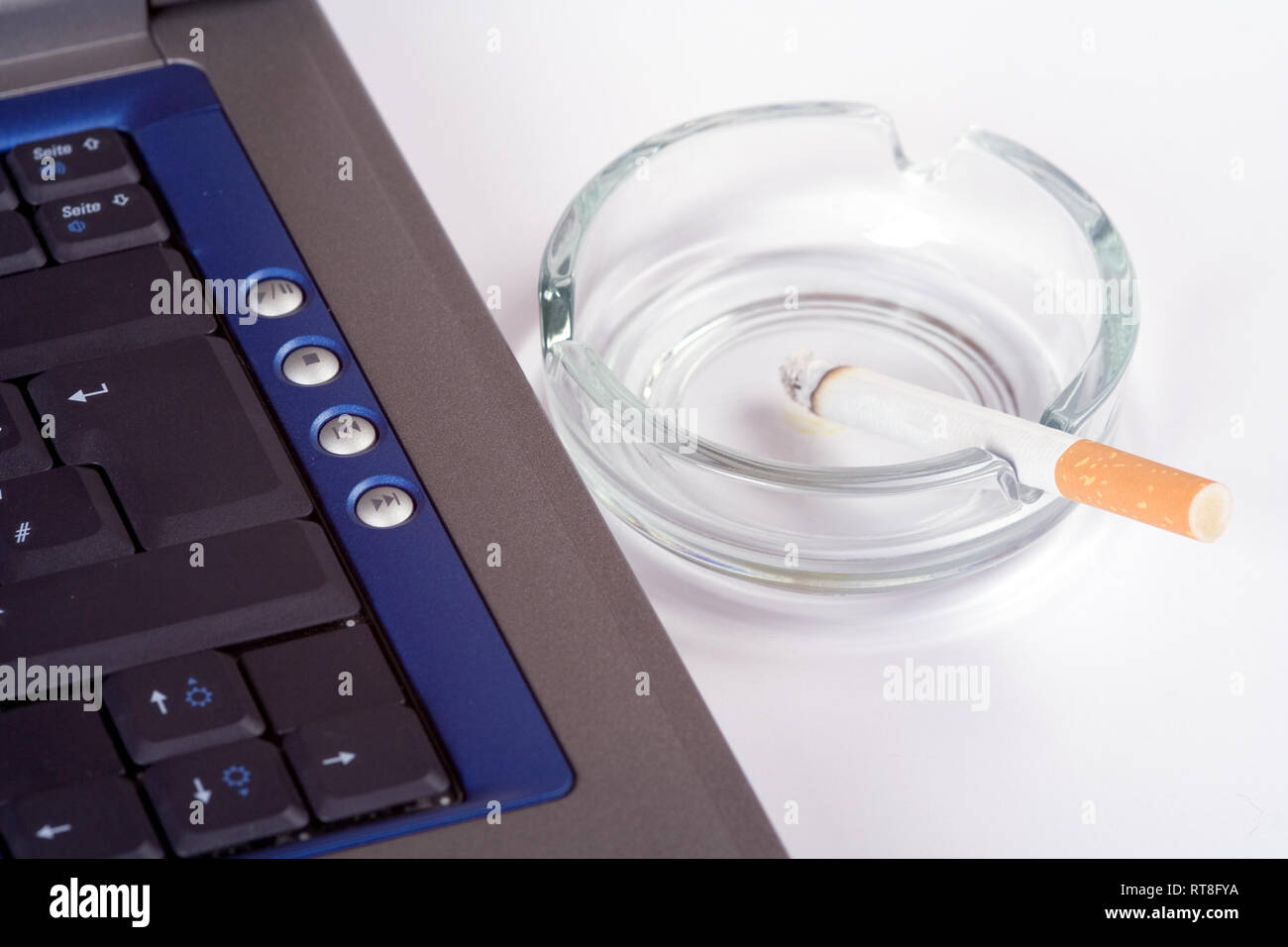 A laptop. Next to it is an ashtray with a smoking cigarette Stock Photo ...