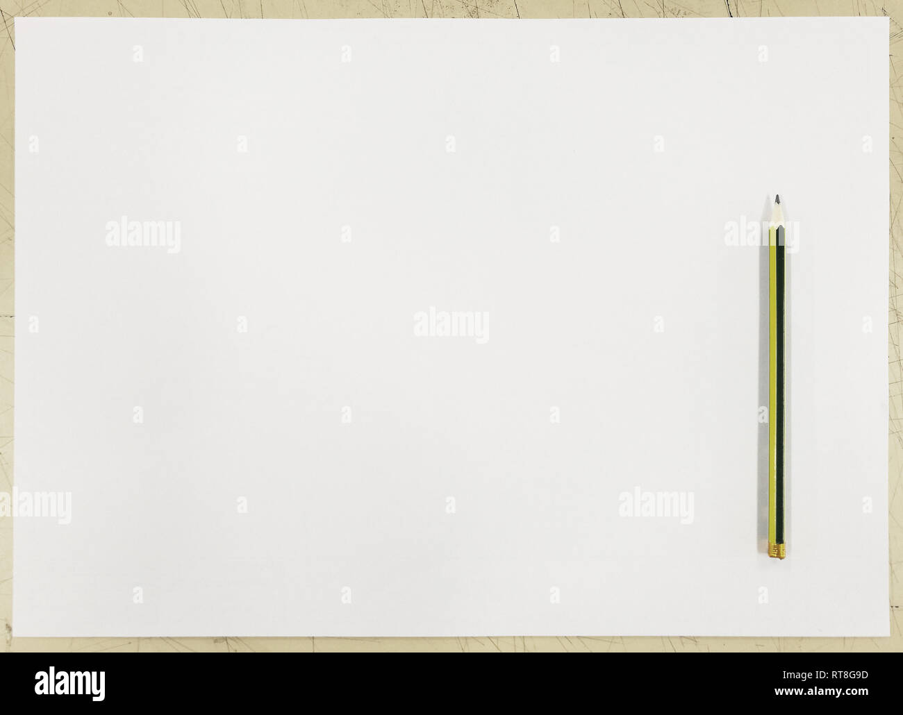 white paper on table and a single pencil on top. Top view background ...