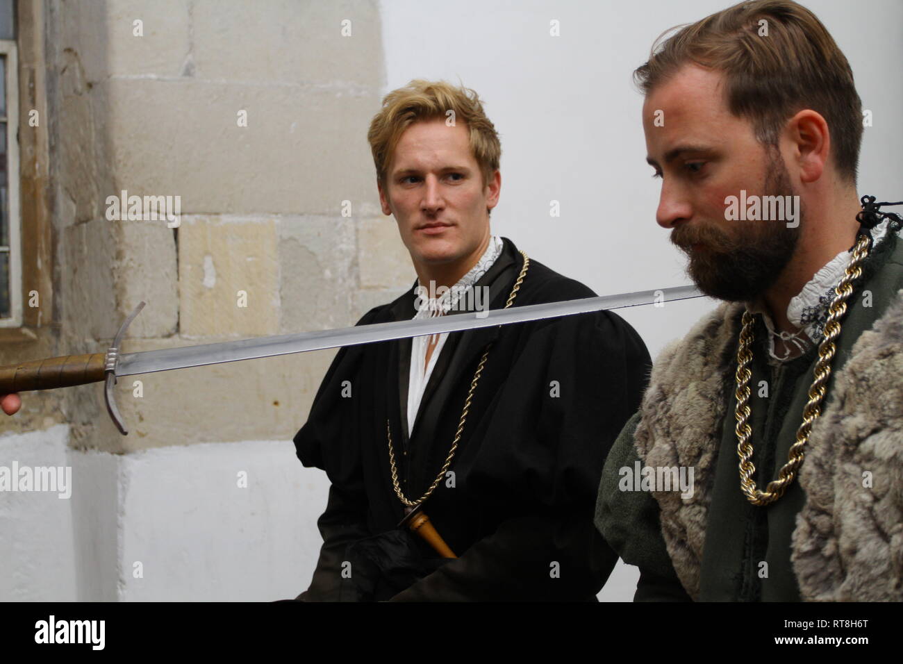 Two young men dressed in authentic Tudor clothing Kneel in front of a ...