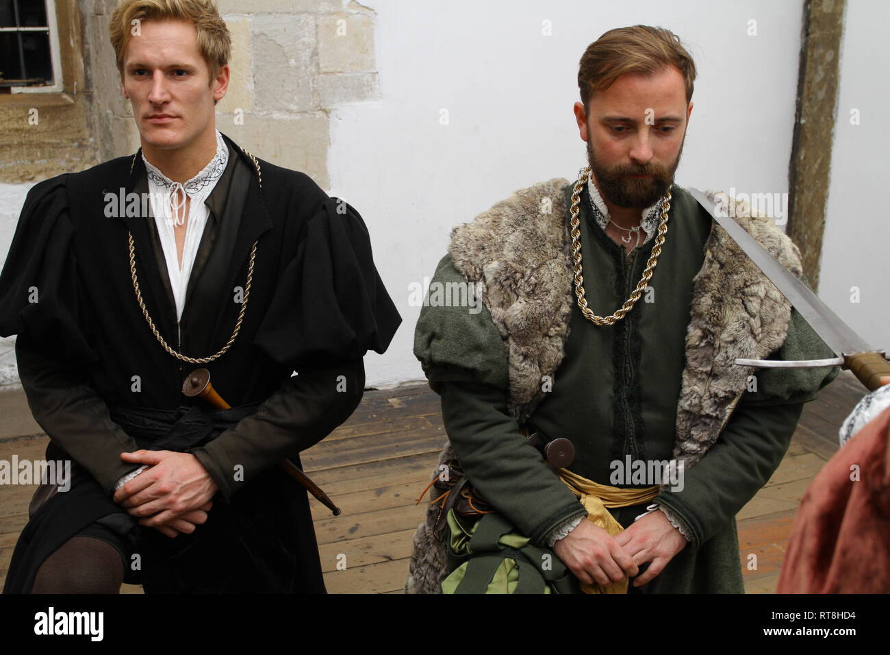 Two young men dressed in authentic Tudor clothing Kneel in front of a ...