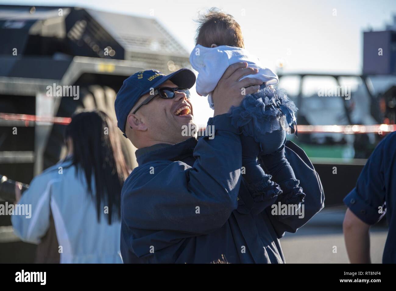 A Coast Guard Cutter Valiant crew member smiles with his child Jan. 29 ...