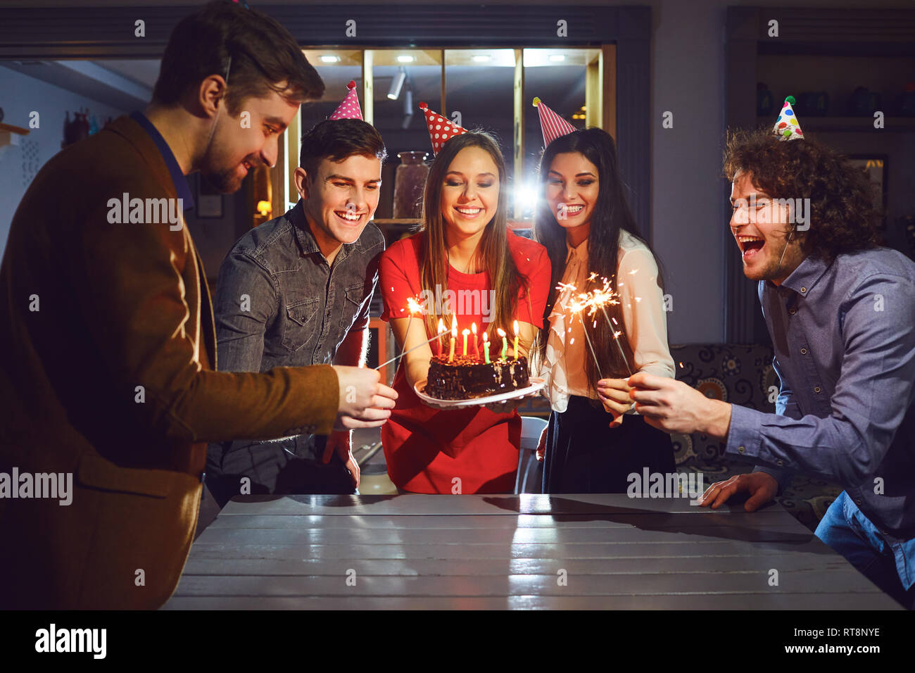 Friends celebrating birthday party indoors Stock Photo - Alamy