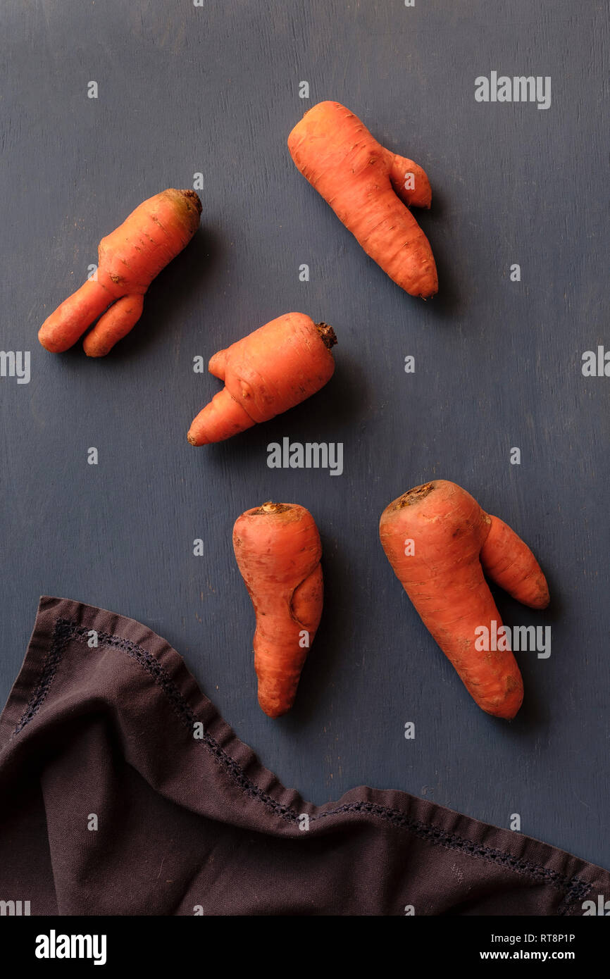 Ugly carrots with doubled shapes on dark background next to brown ...