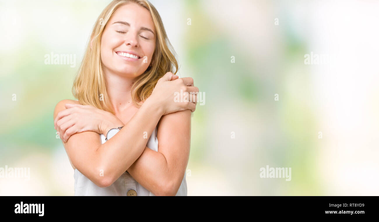 Beautiful young woman over isolated background Hugging oneself happy ...