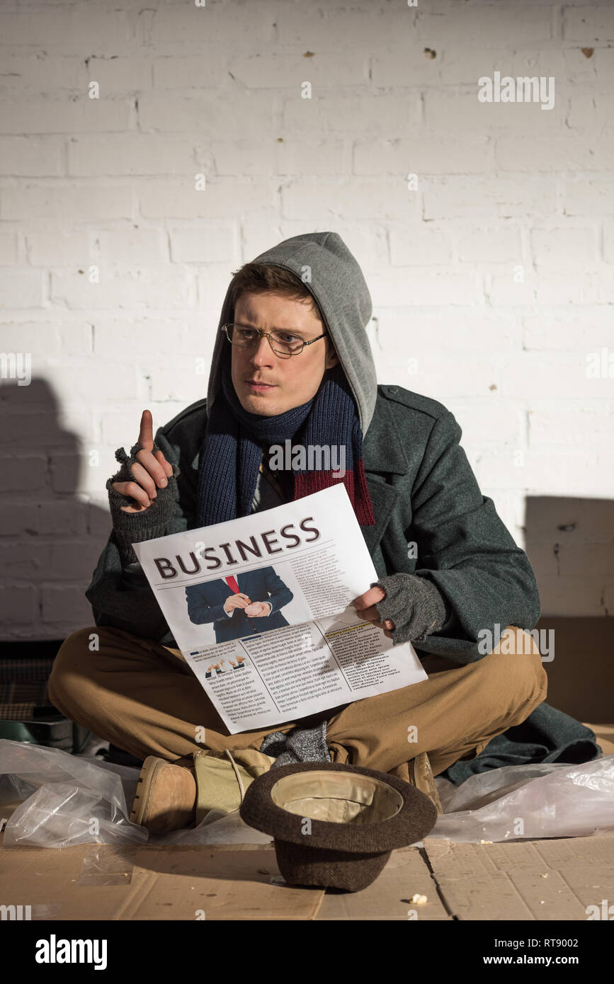 homeless man reading business newspaper and showing idea sign Stock ...