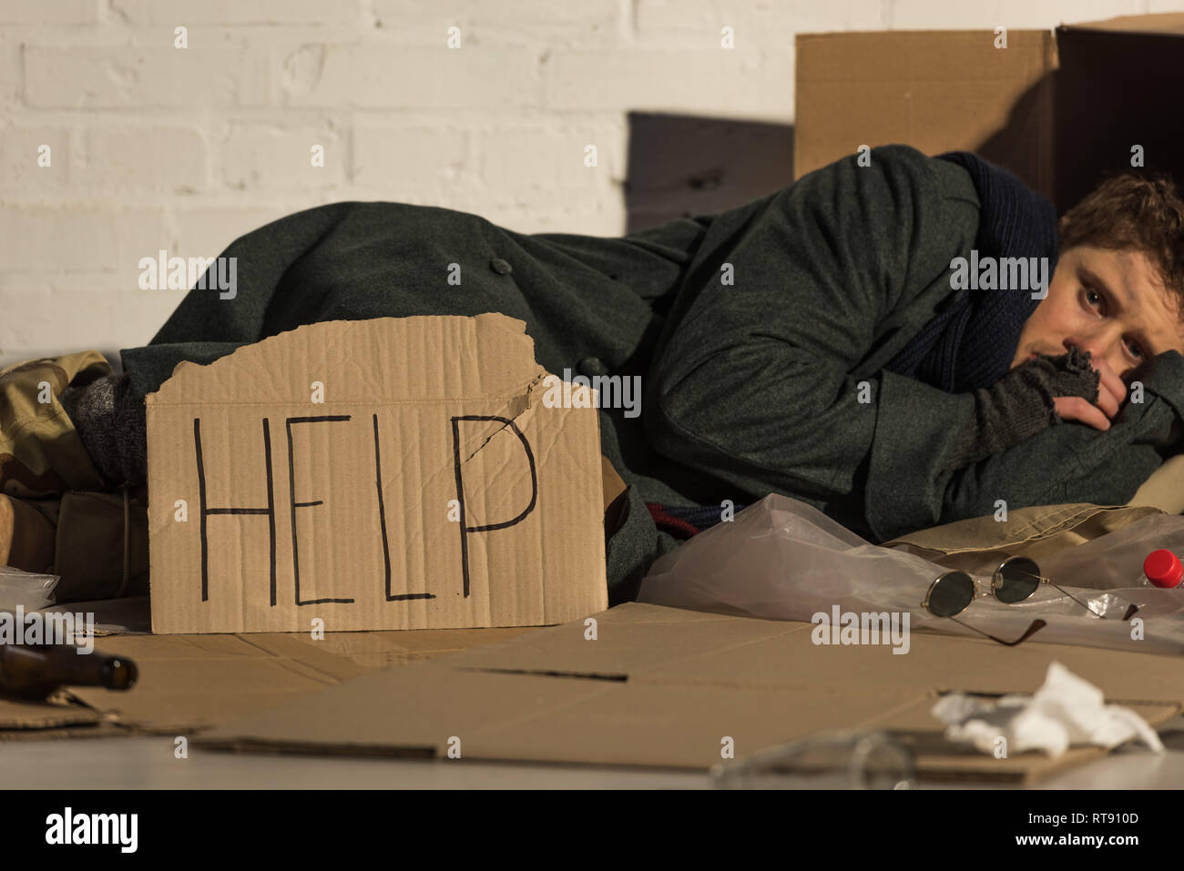 homeless poor man lying on cardboard by white brick wall Stock Photo ...