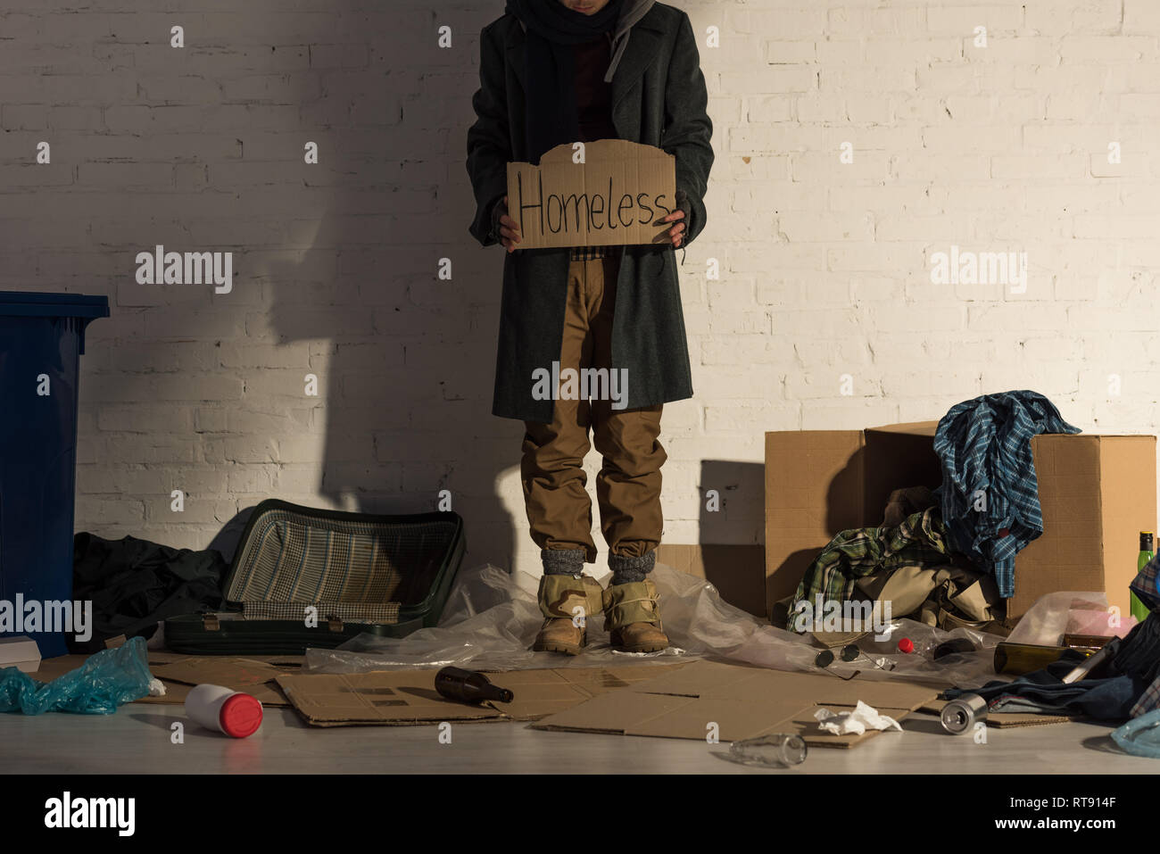 cropped view of houseless man holding piece of cardboard with "homeless ...
