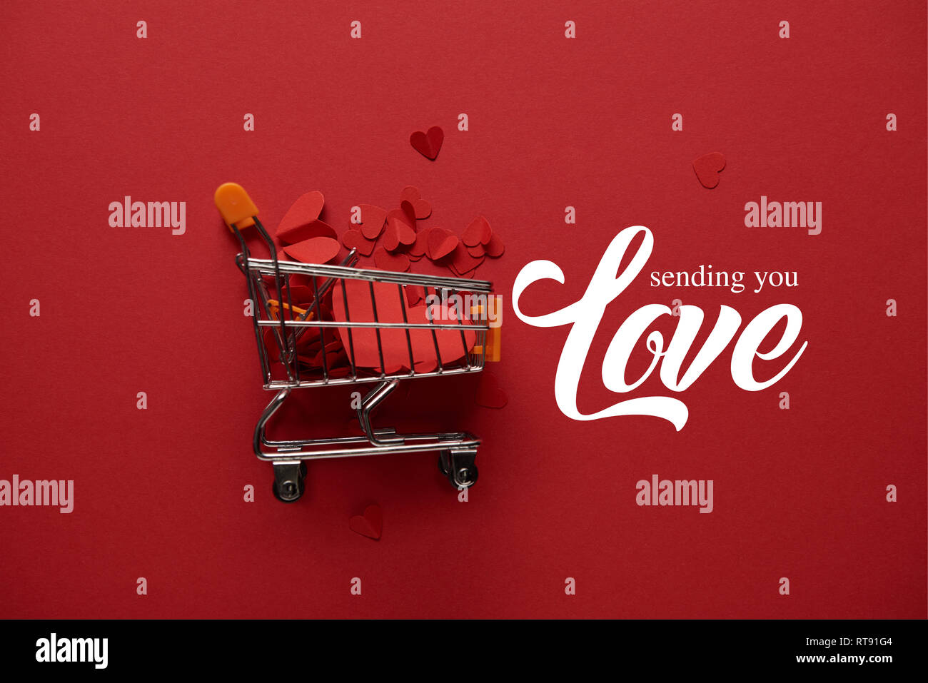top view of toy shopping cart with decorative paper cut hearts on red ...