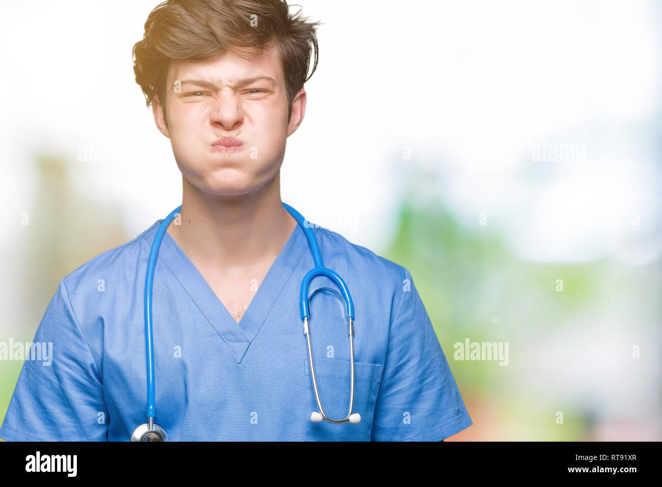 Young doctor wearing medical uniform over isolated background puffing ...