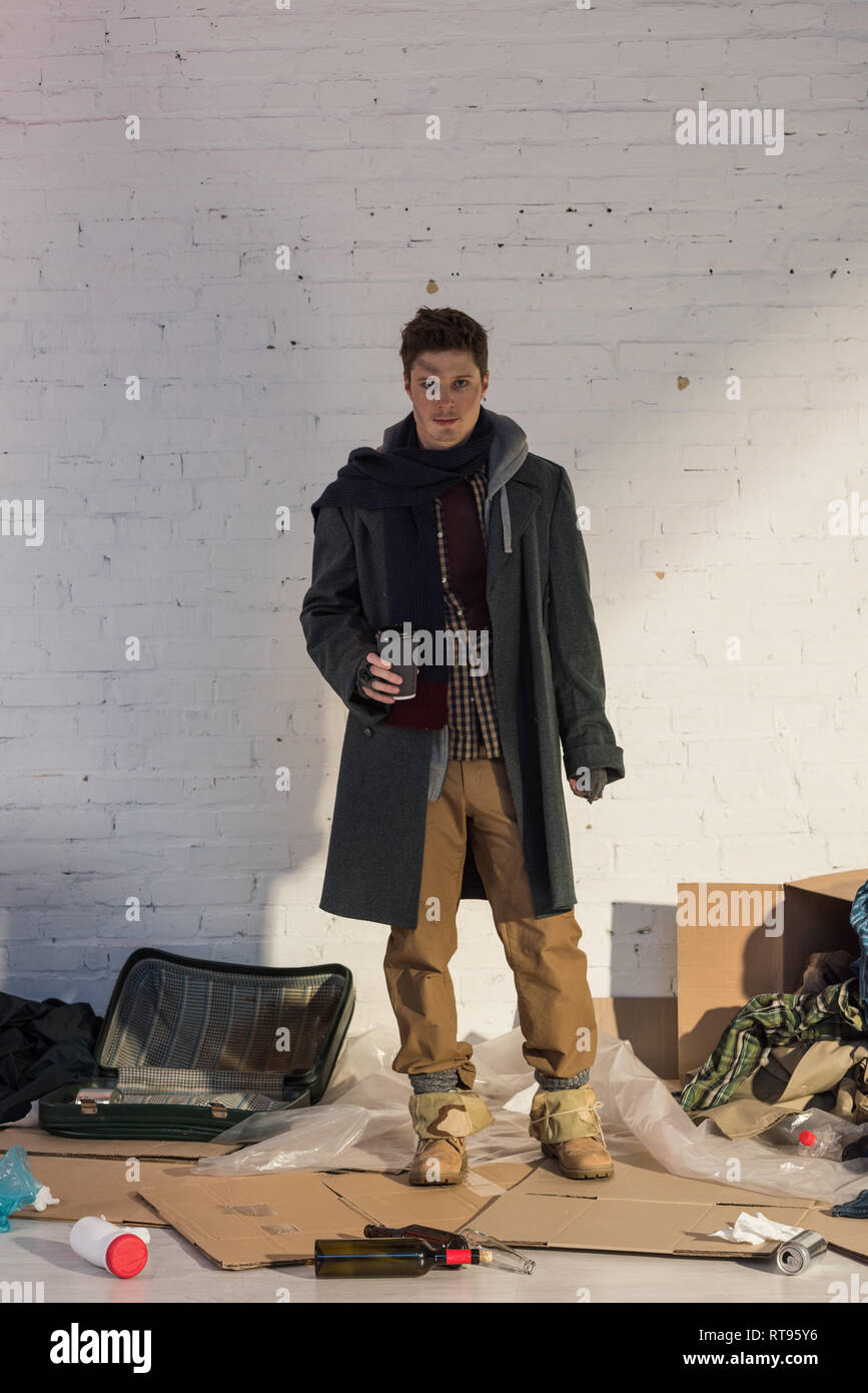 homeless man standing on cardboard and holding disposable cup Stock ...