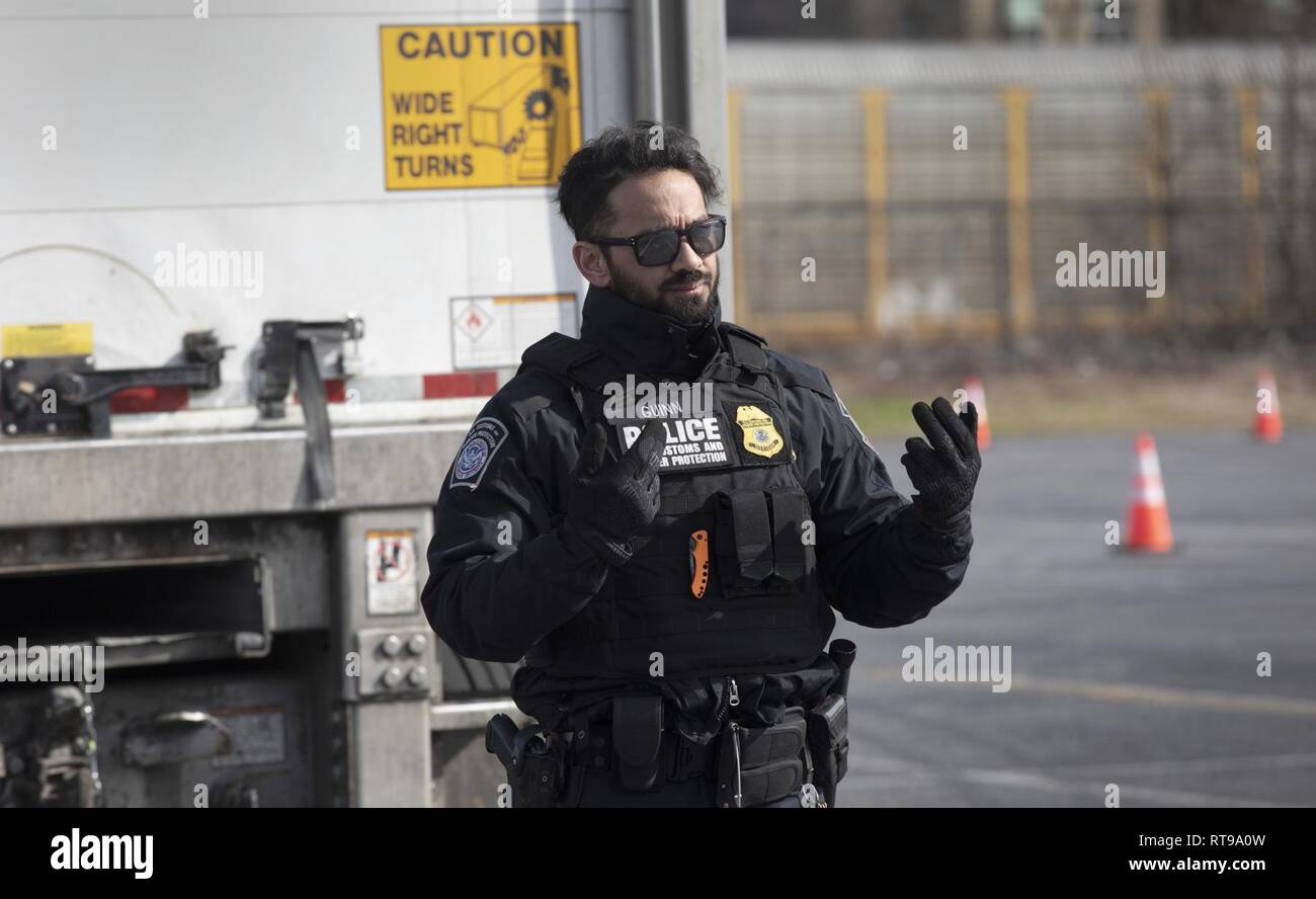 A U.S. Customs and Border Protection officer directs vehicles during ...