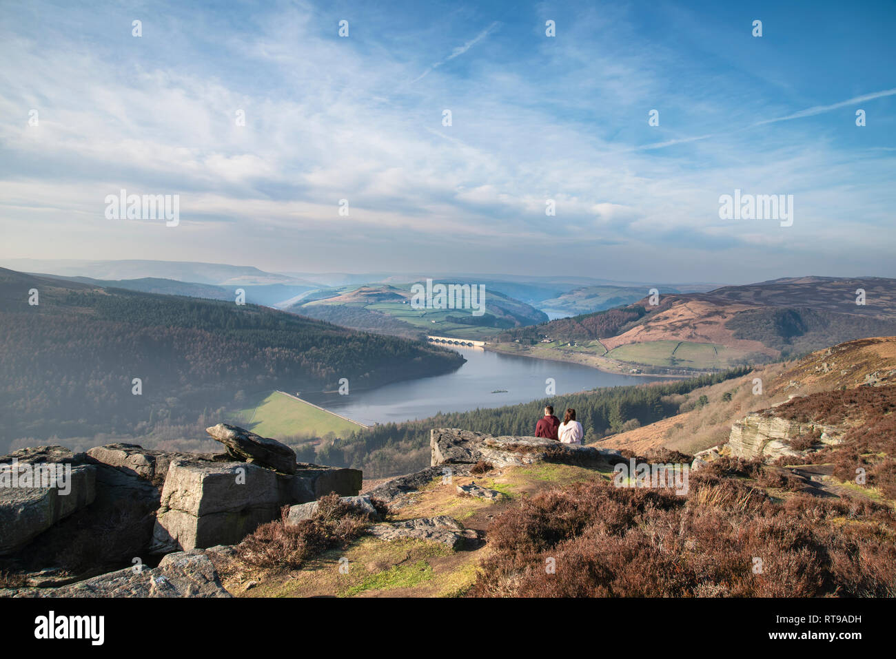 Young couple sat on Bamford Edge in the Peak District looking out over ...