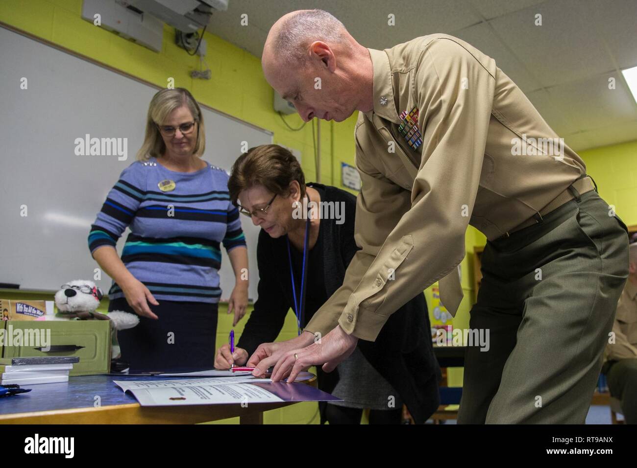 U.S. Marine Lt. Col. Sean Walsh, right, and Kathy Leffler, center, sign ...