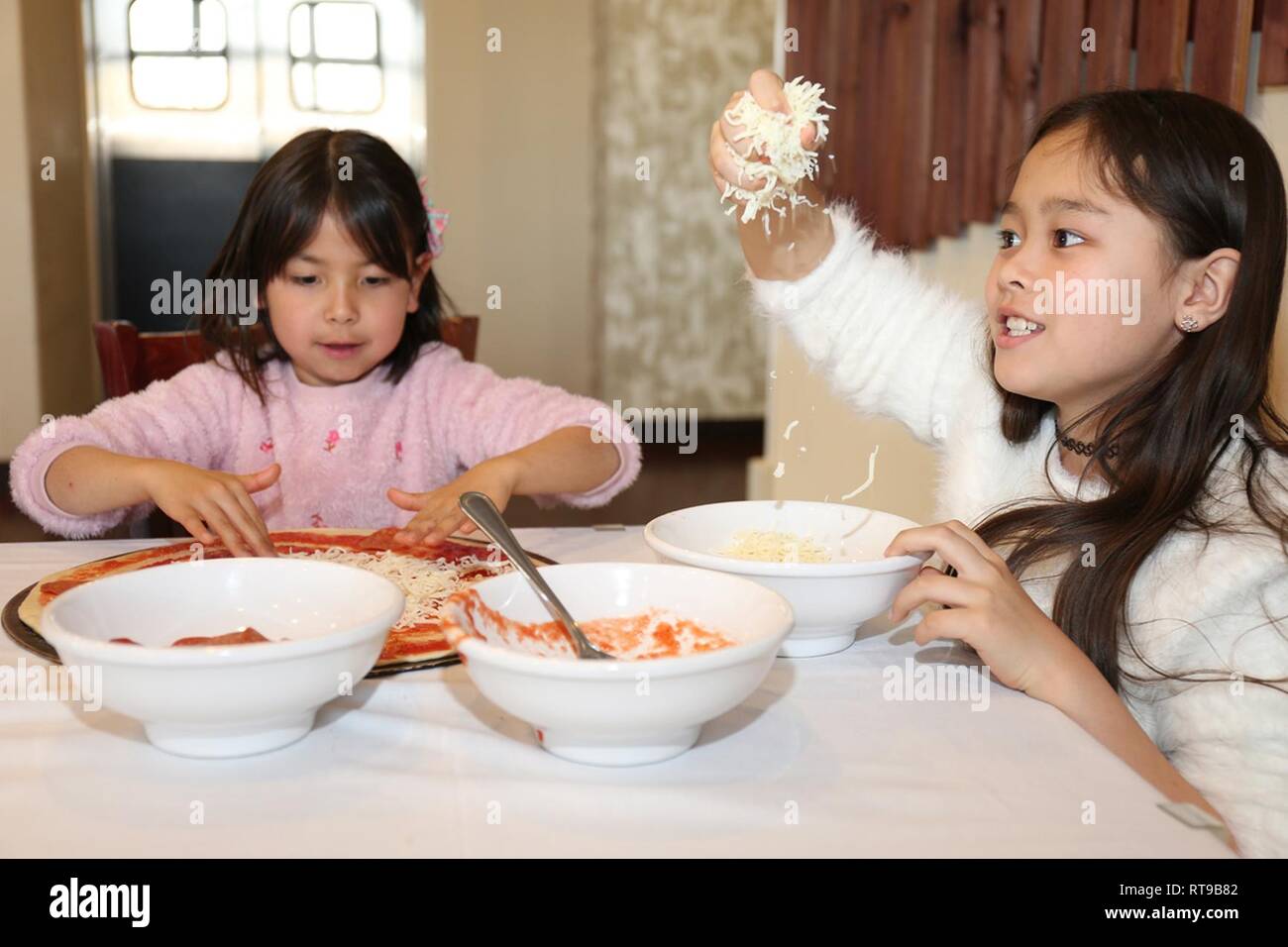 Nine-year-old Erin Hutton, right, grabs a handful of mozzarella cheese ...