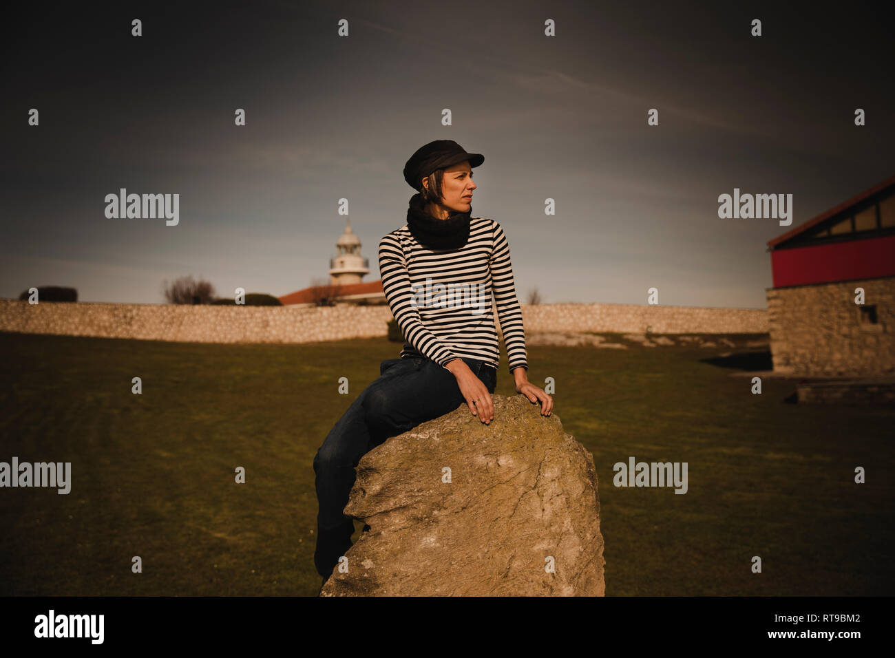 Elegant lady in cap sitting on seat on coast near waving sea Stock ...