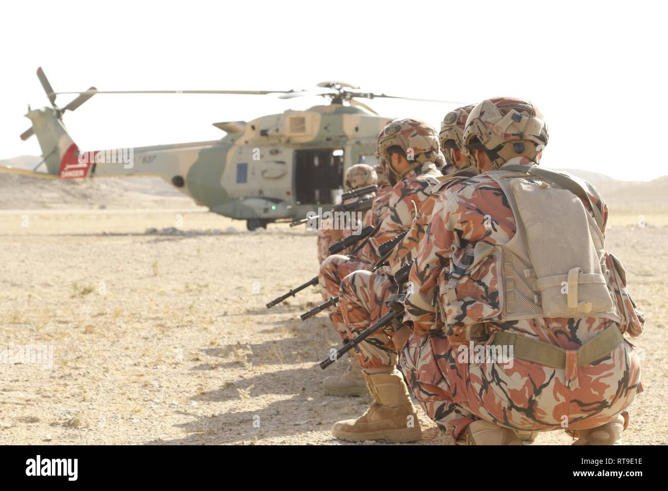 A squad of Omani troops kneels in a ready position before tactically ...