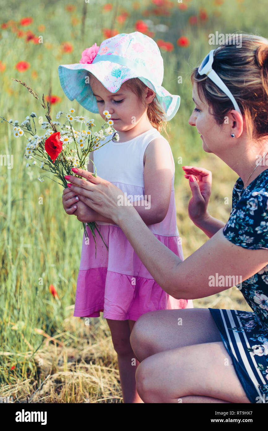 Mother and her little daughter in the field of wild flowers. Little ...