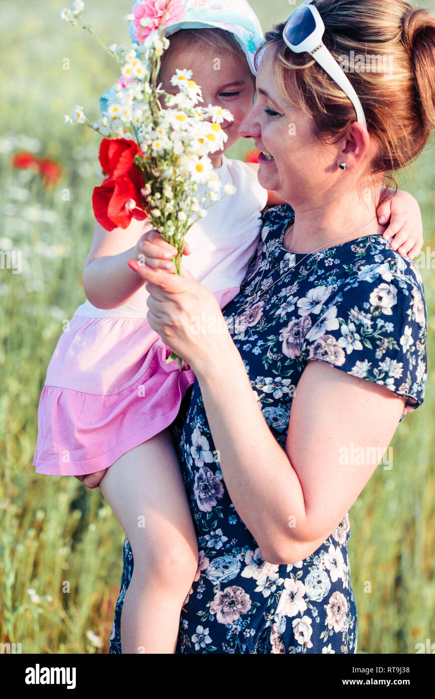 Mother and her little daughter in the field of wild flowers. Little ...