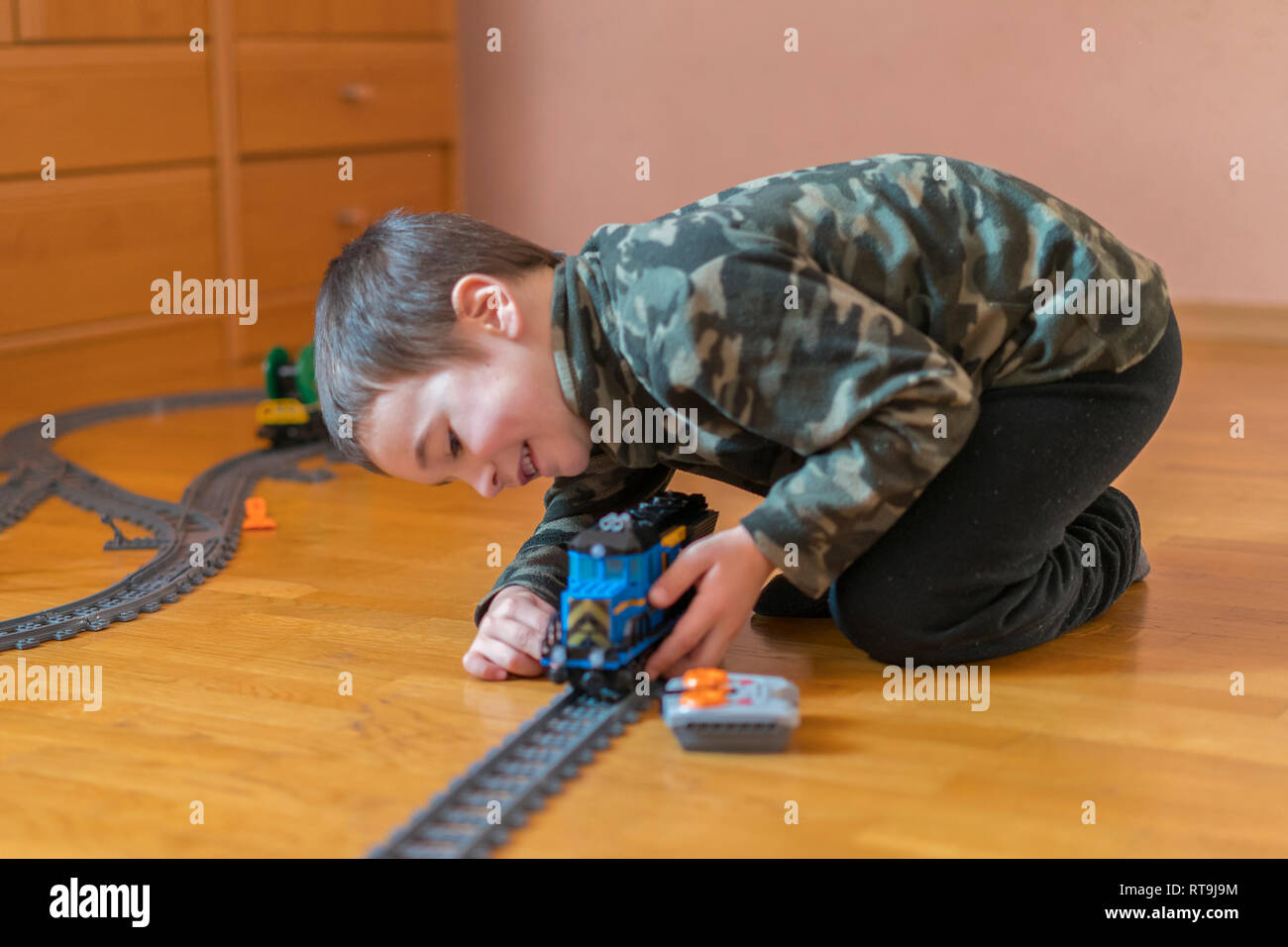 Five year old boy playing on the floor by rail. Little boy playing with ...