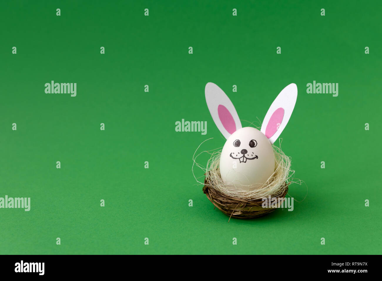 Busket with Easter bunny made from eggs and paper ears on green pastel ...