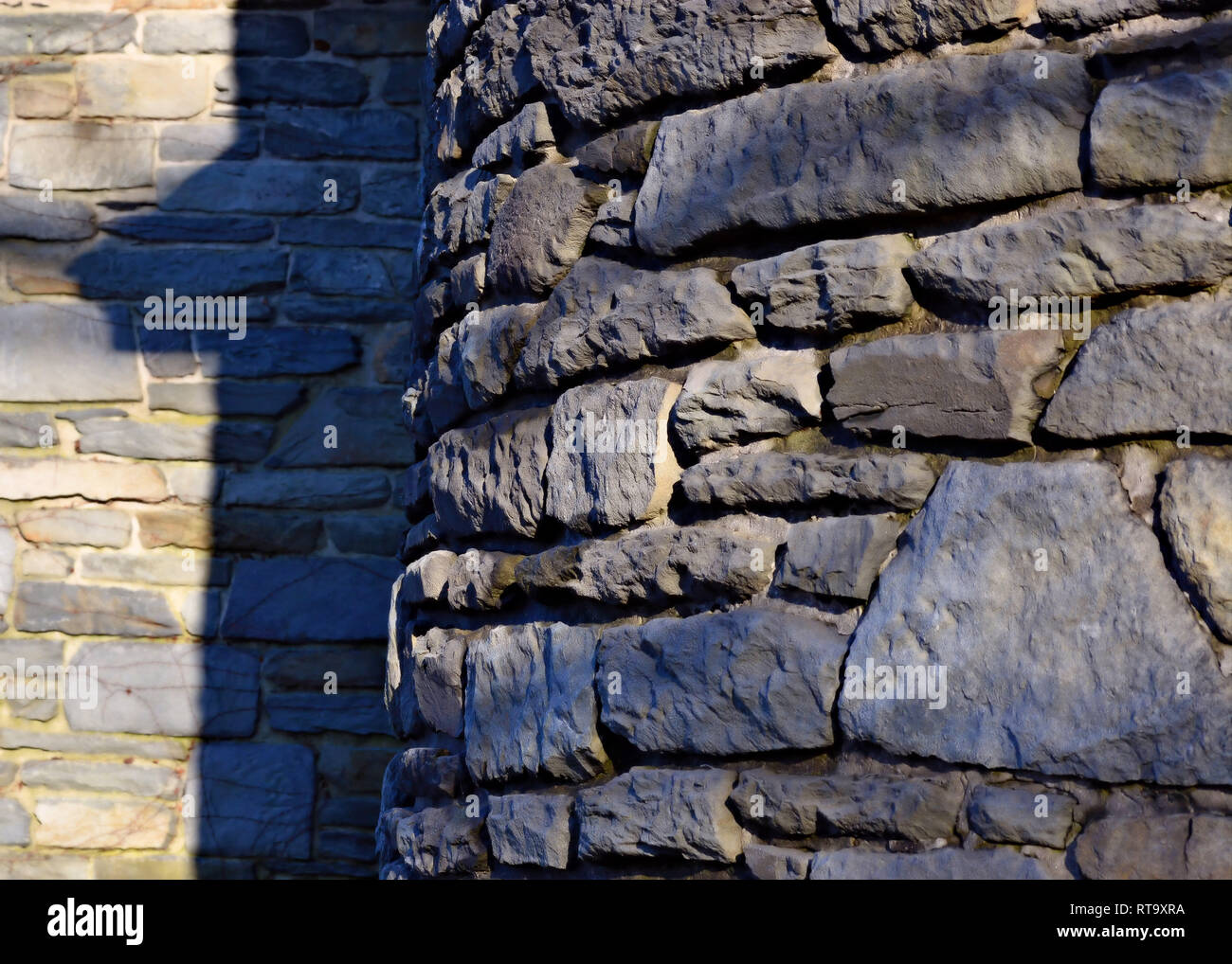 Curved gray stone wall casting shadow Stock Photo - Alamy