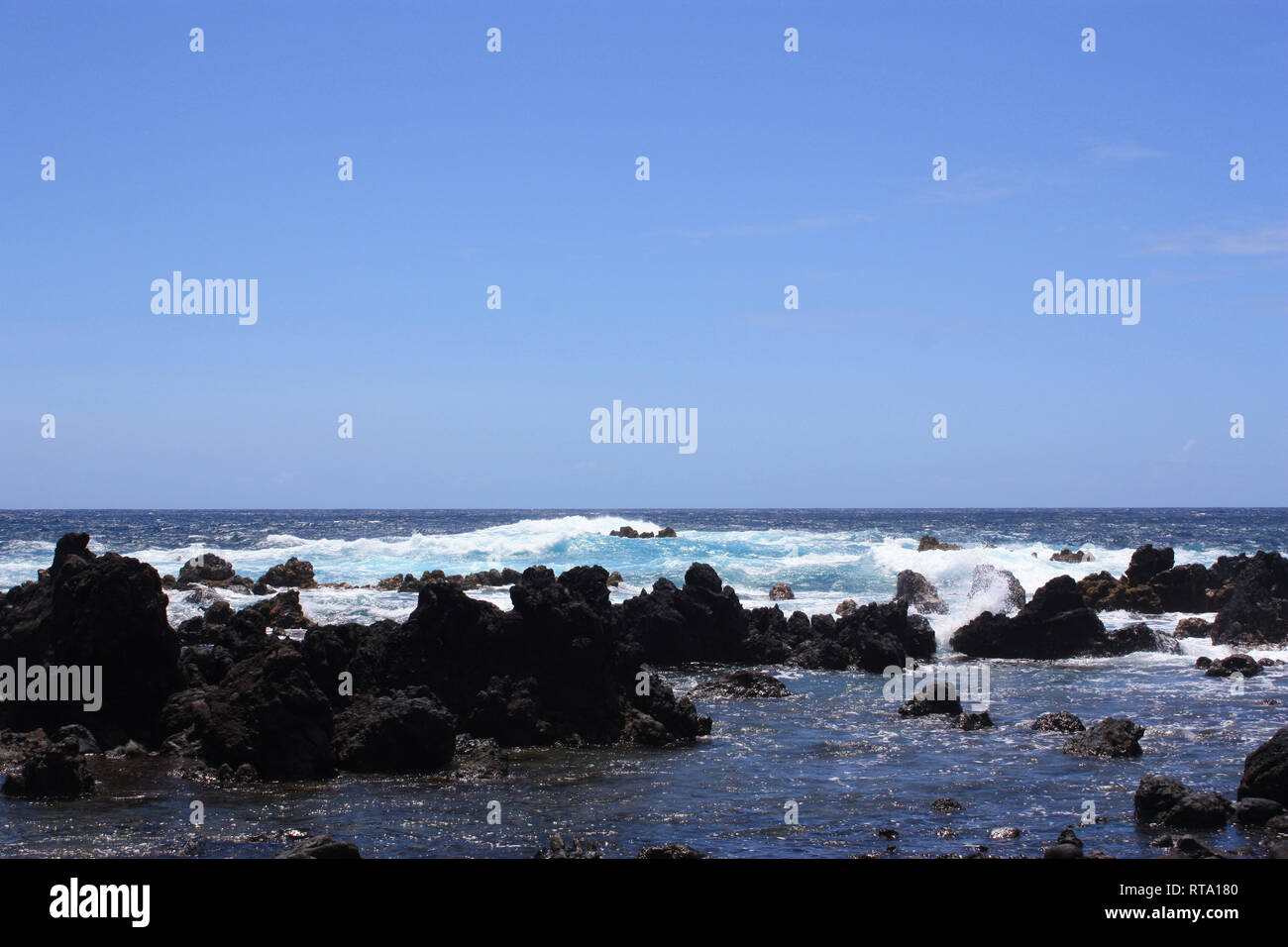 Rocky, black lava shoreline fronting deep blue Pacific Ocean at ...