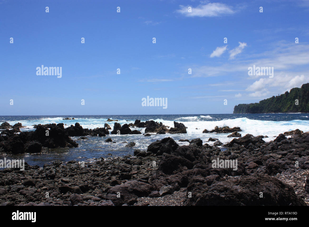 Rocky, black lava shoreline fronting deep blue Pacific Ocean at ...