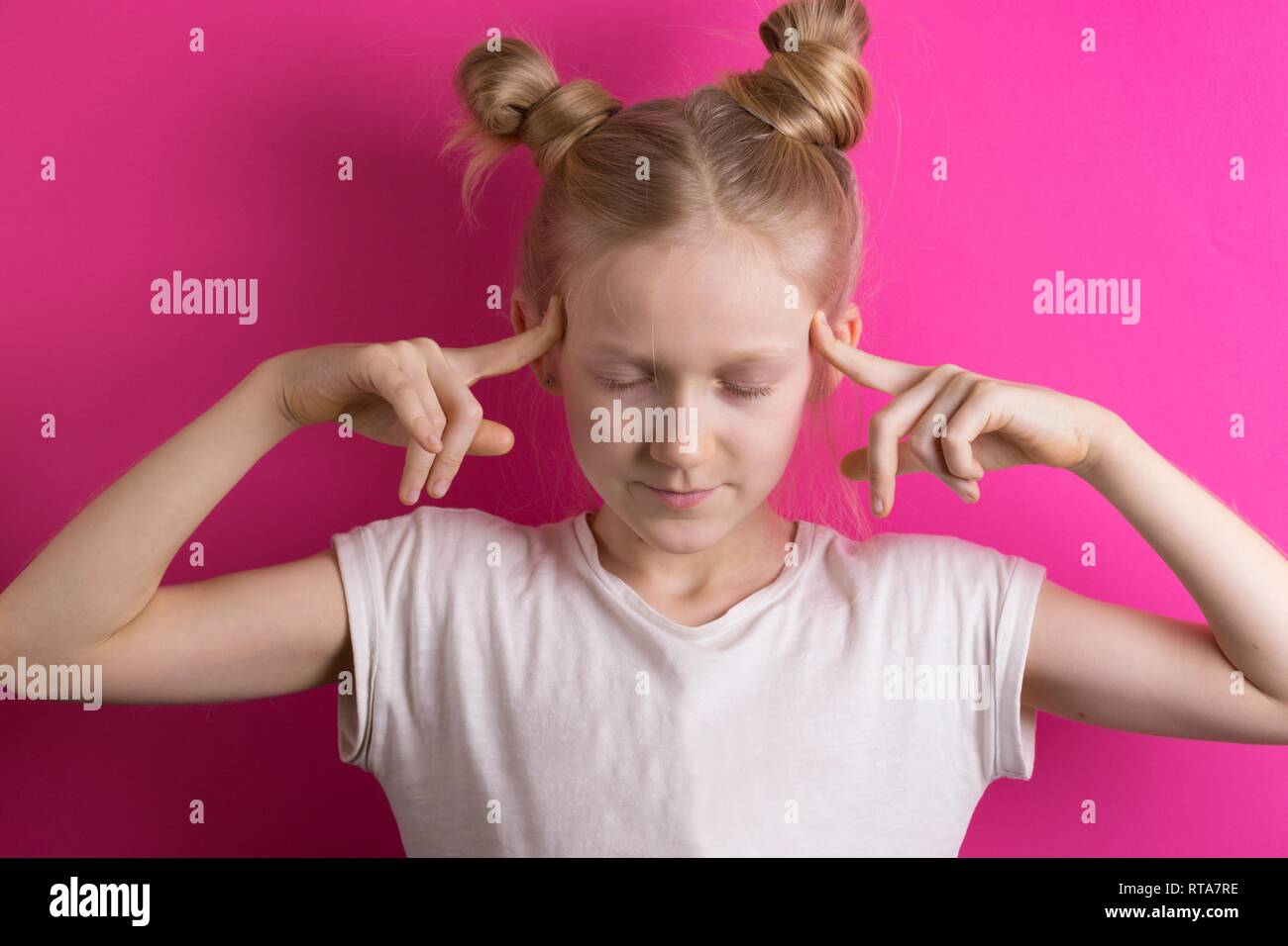 little beautiful girl blonde on a pink background. the girl is thinking ...