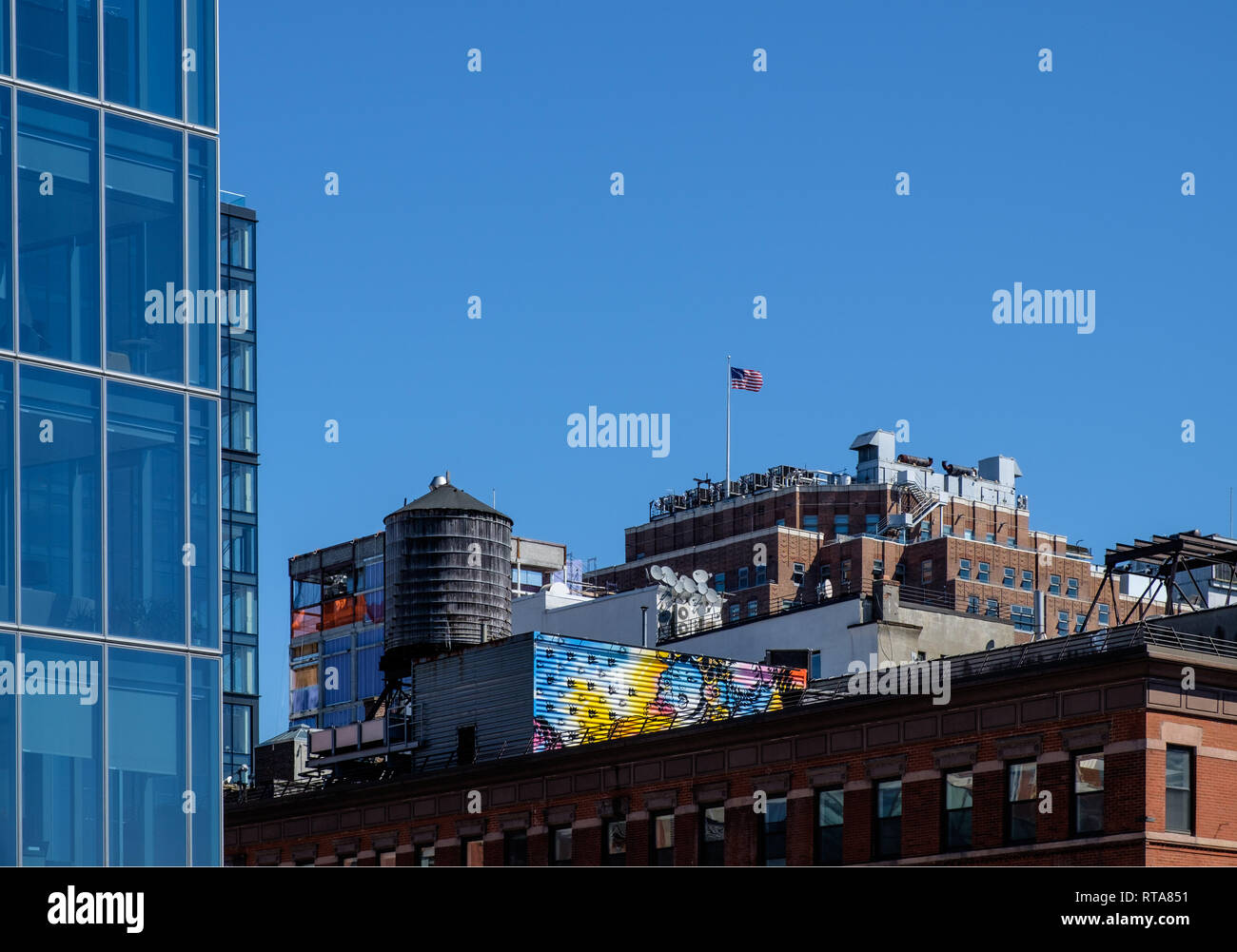 Rooftops with American flag, old round water tank, & painted graffiti ...
