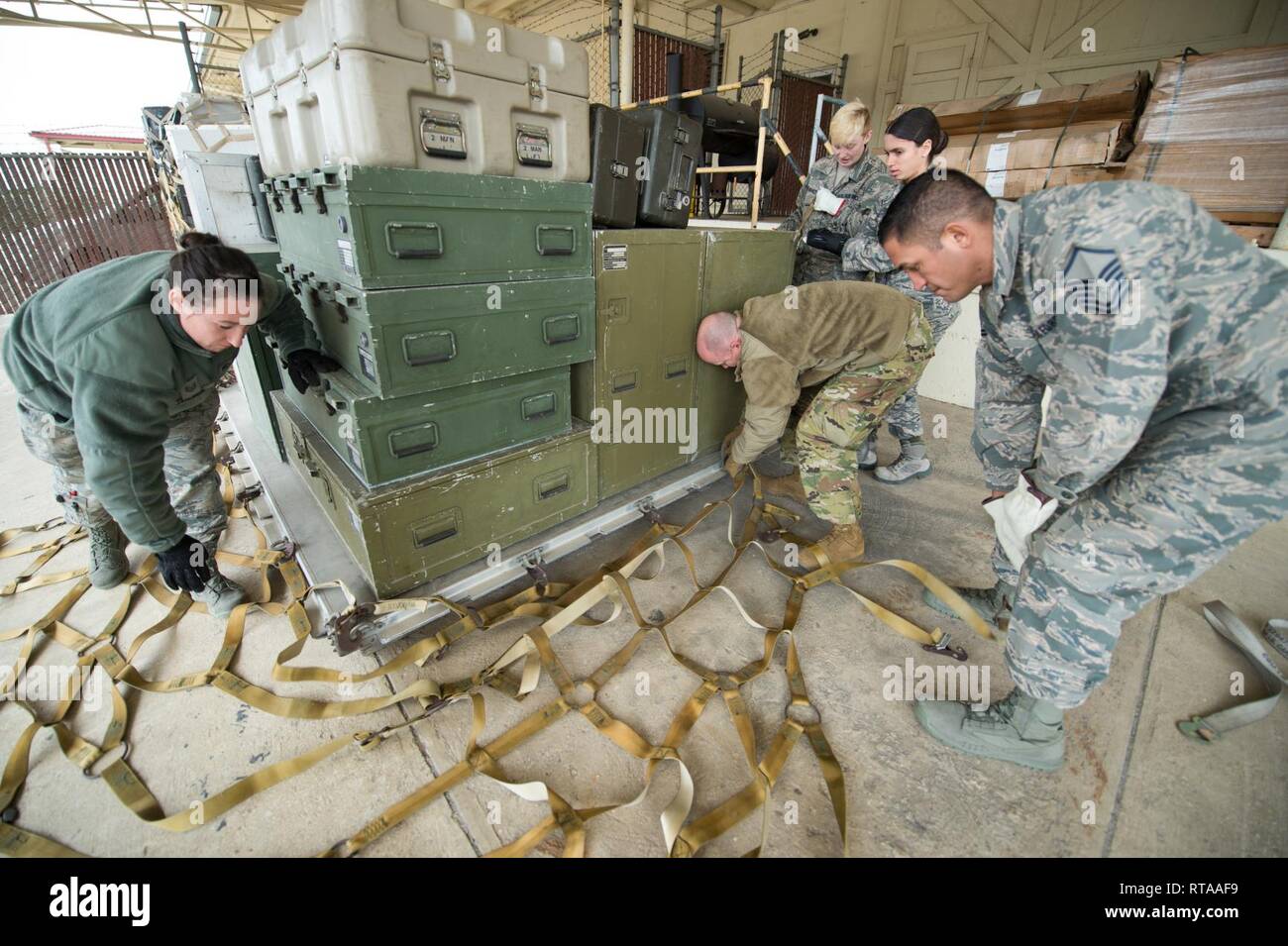 U.S. Air Force Airmen secure straps during cargo prep pallet build up ...