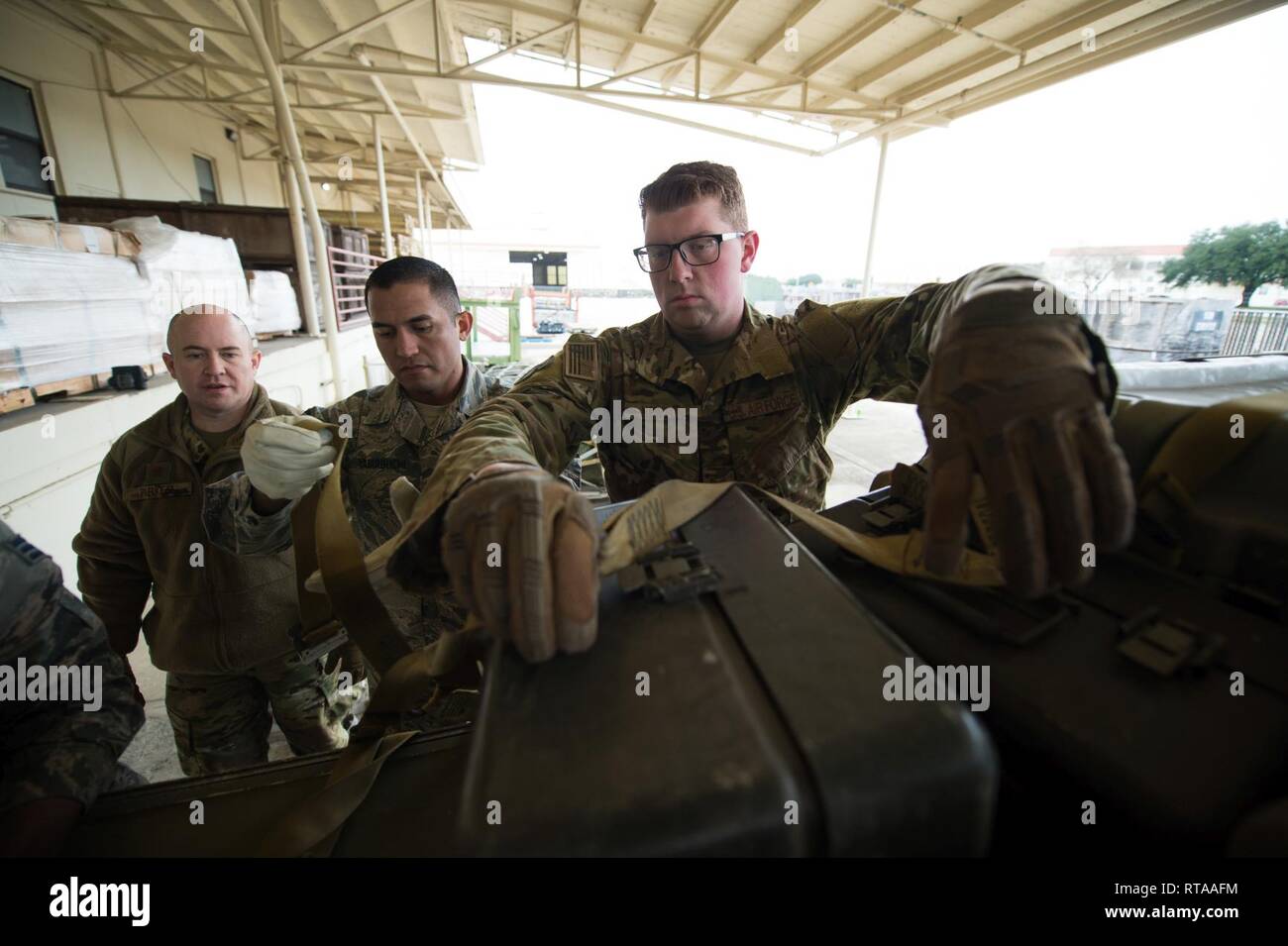 U.S. Air Force Airmen secure straps during cargo prep pallet build up ...