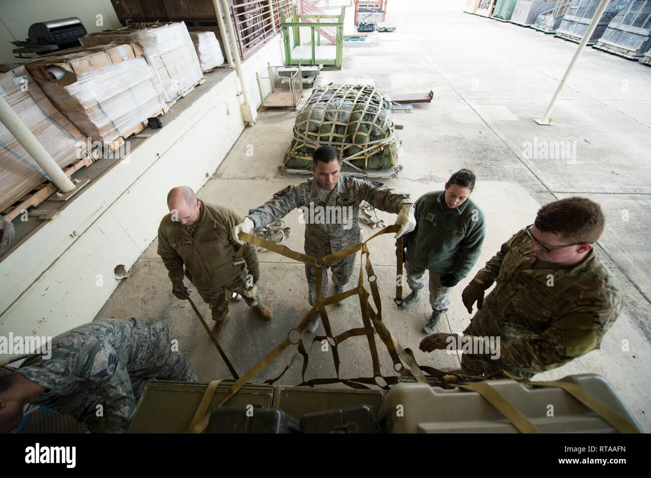 U.S. Air Force Airmen secure straps during cargo prep pallet build up ...
