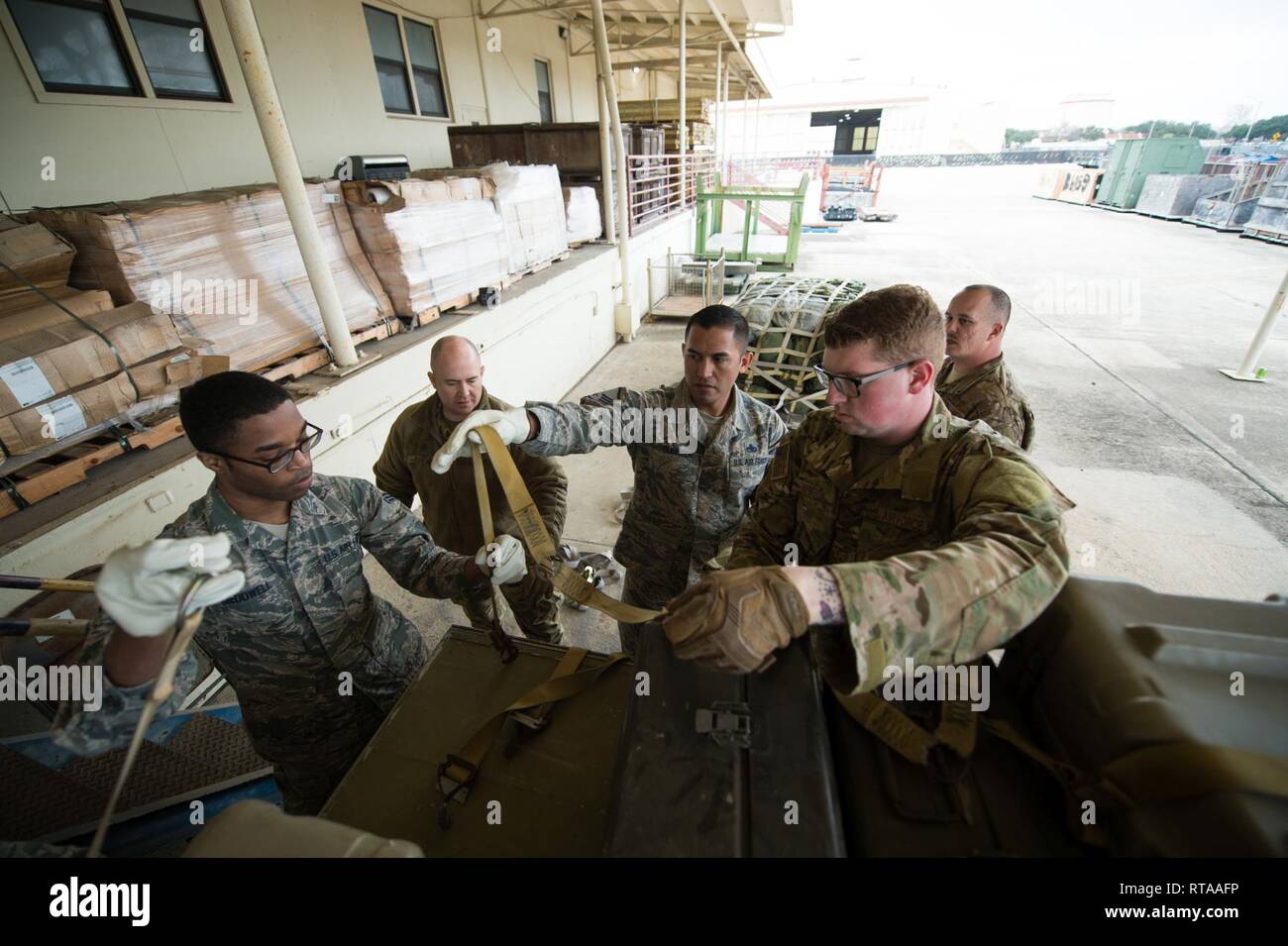 U.S. Air Force Airmen secure straps during cargo prep pallet build up ...