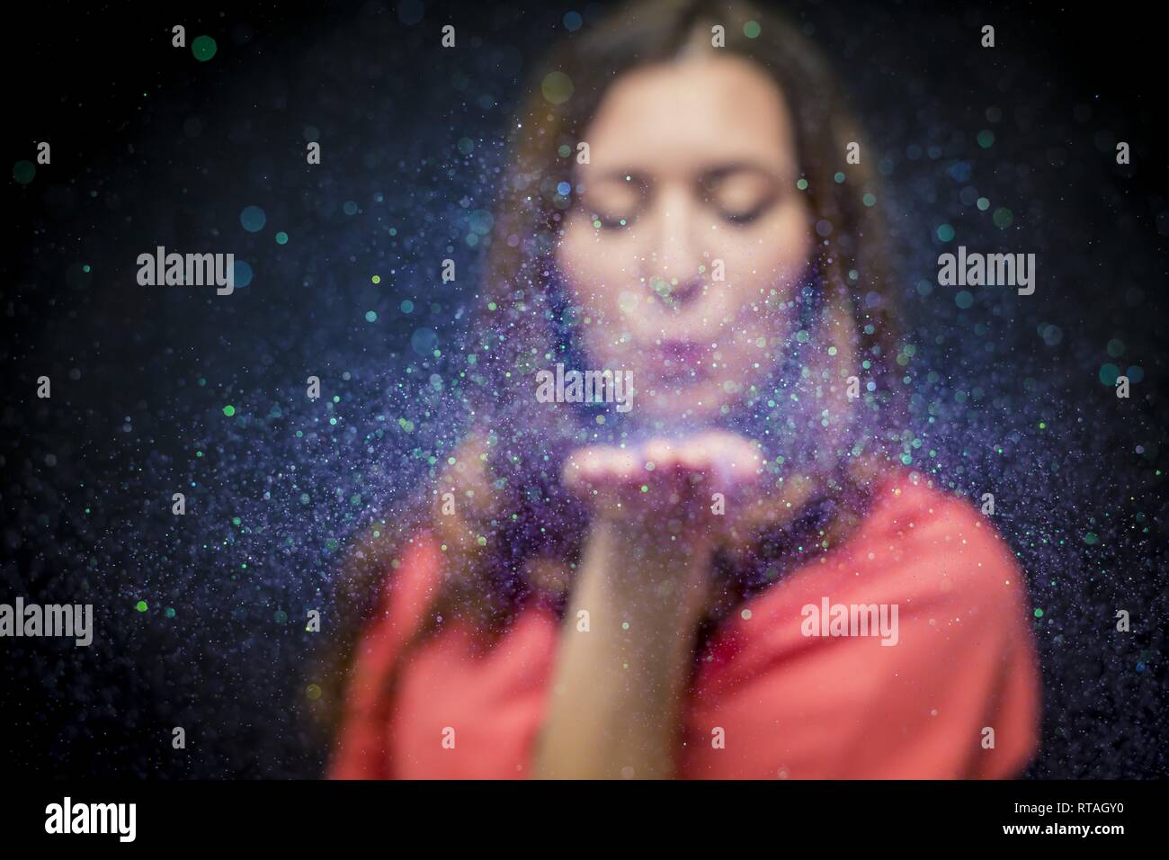 Girl blowing colored glitter from her hand Stock Photo - Alamy