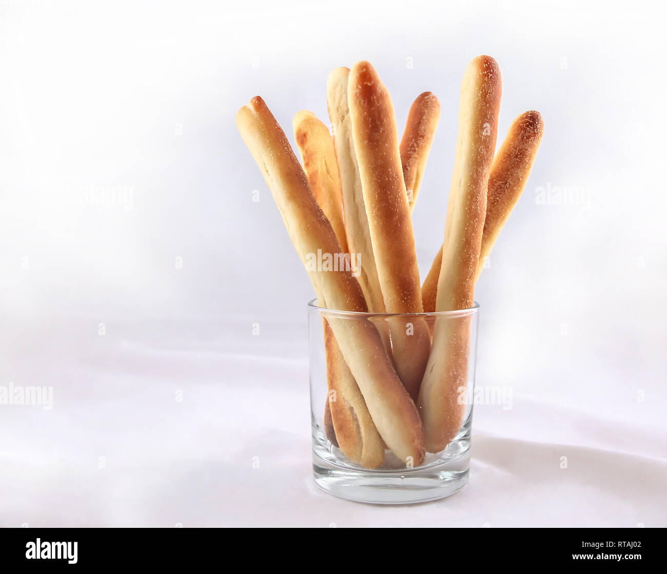 Long straight breadsticks are in a glass beaker with selective focus ...