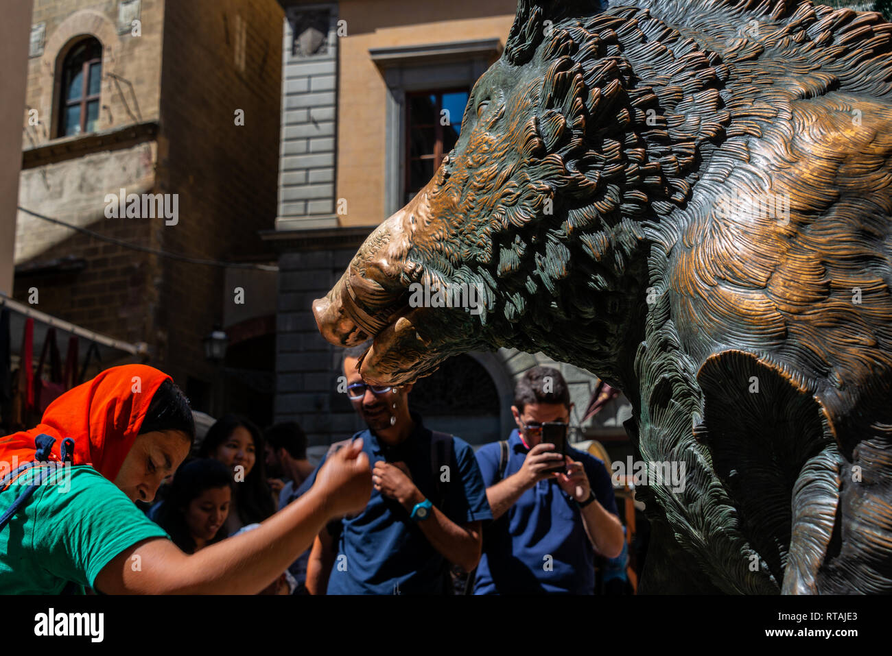 Tourist touching fortune boar pig in Florence. the legend is to touch ...