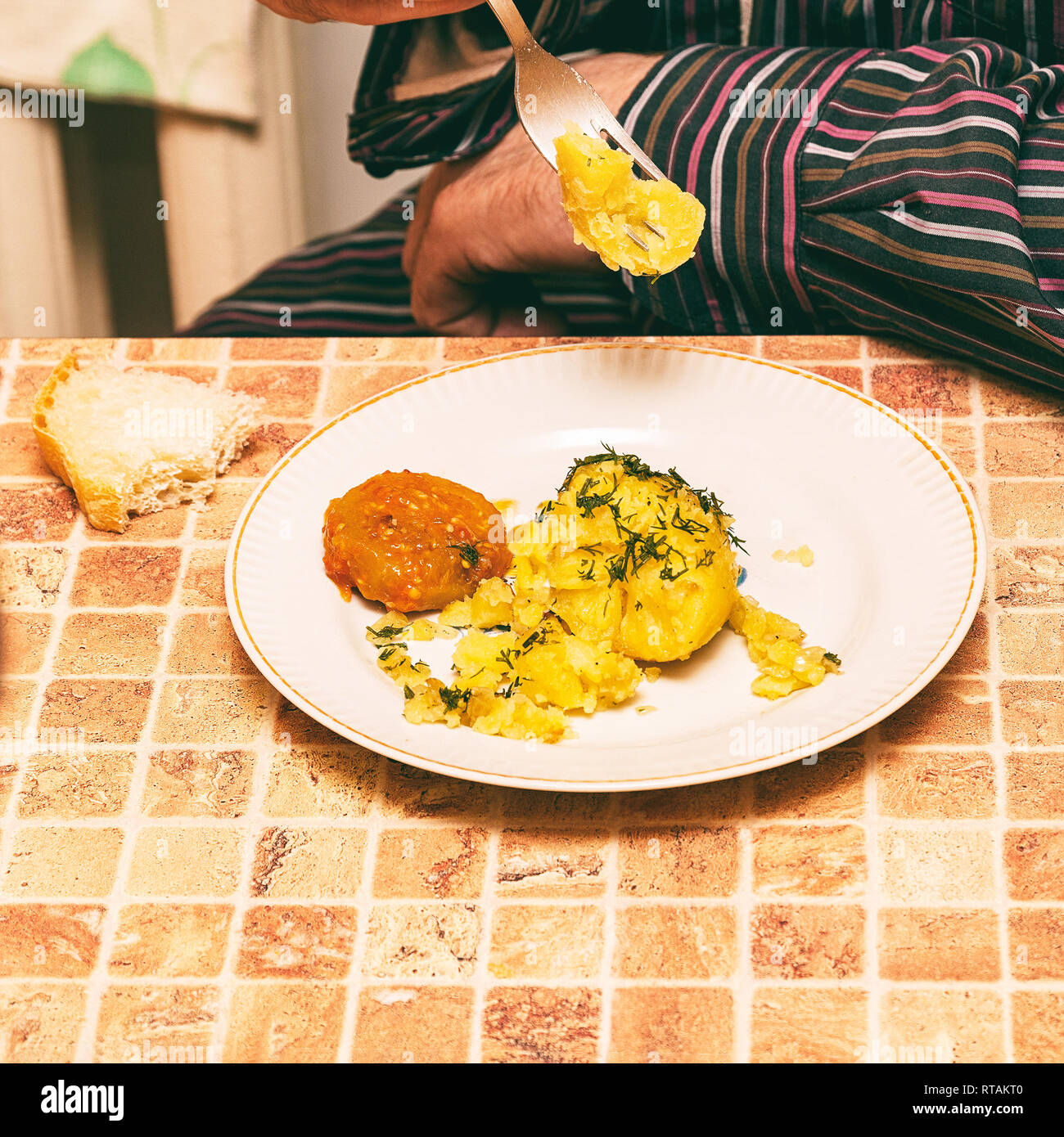 Man at the table in the kitchen eating potatoes Stock Photo - Alamy