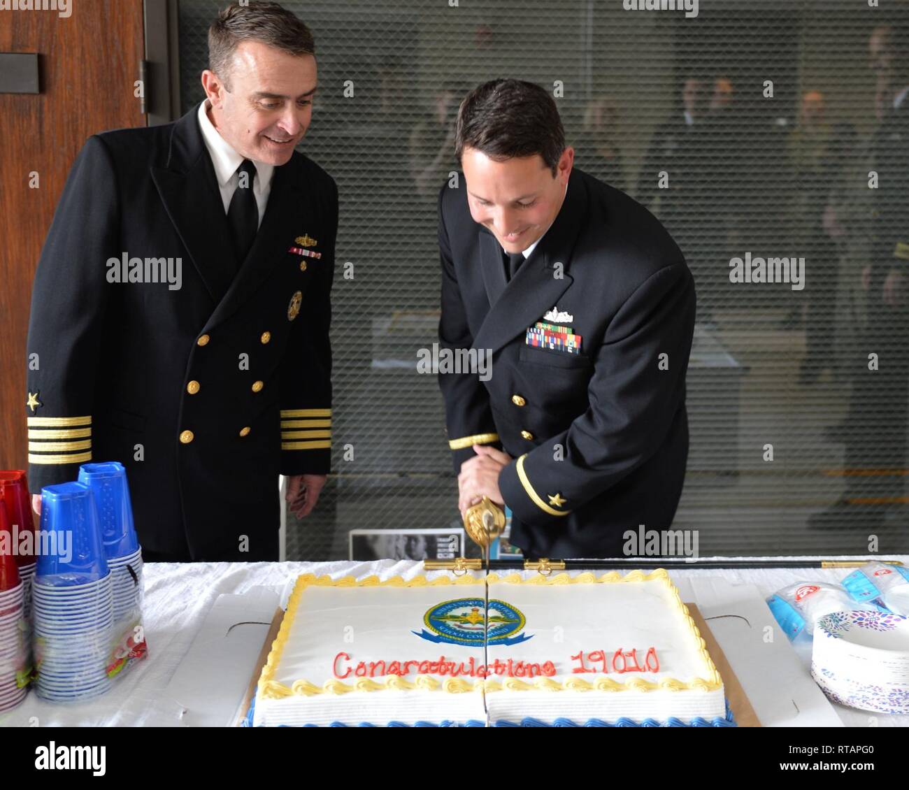 Capt. Joseph Cahill and Ensign William Robins cut a cake to celebrate ...