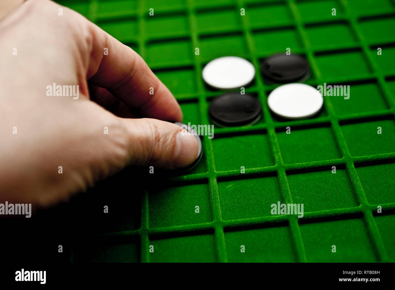 hand playing a disc on the board, during a Reversi or Othello game ...