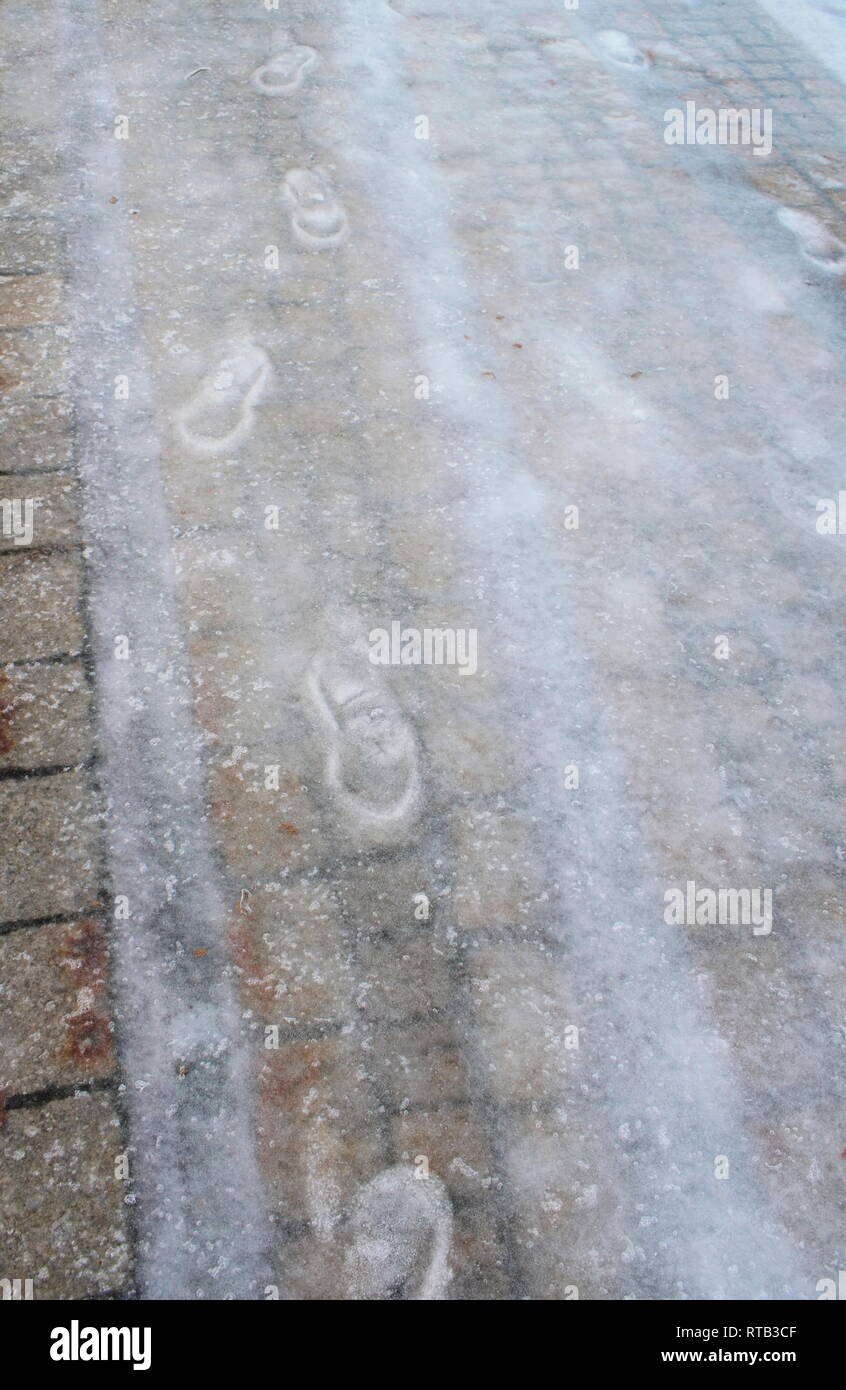 Footprints in the snow have frozen into ice covering the pavement Stock ...