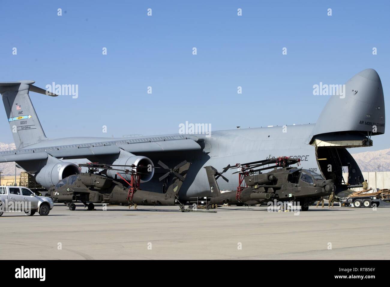 Airmen, Soldiers, and personnel prepare to load Apache Helicopters into ...