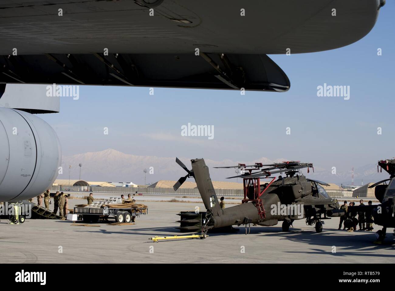 Airmen, Soldiers, and personnel prepare to load Apache Helicopters into ...
