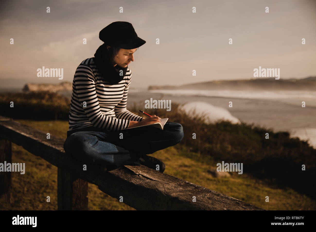 Elegant lady in cap taking notes in notepad and sitting on seat on ...