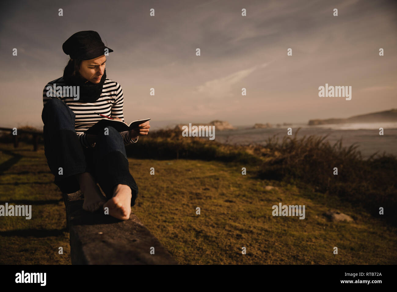 Elegant lady in cap taking notes in notepad and sitting on seat on ...
