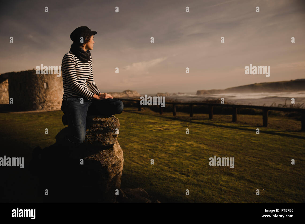 Elegant lady in cap sitting on seat on coast near waving sea Stock ...