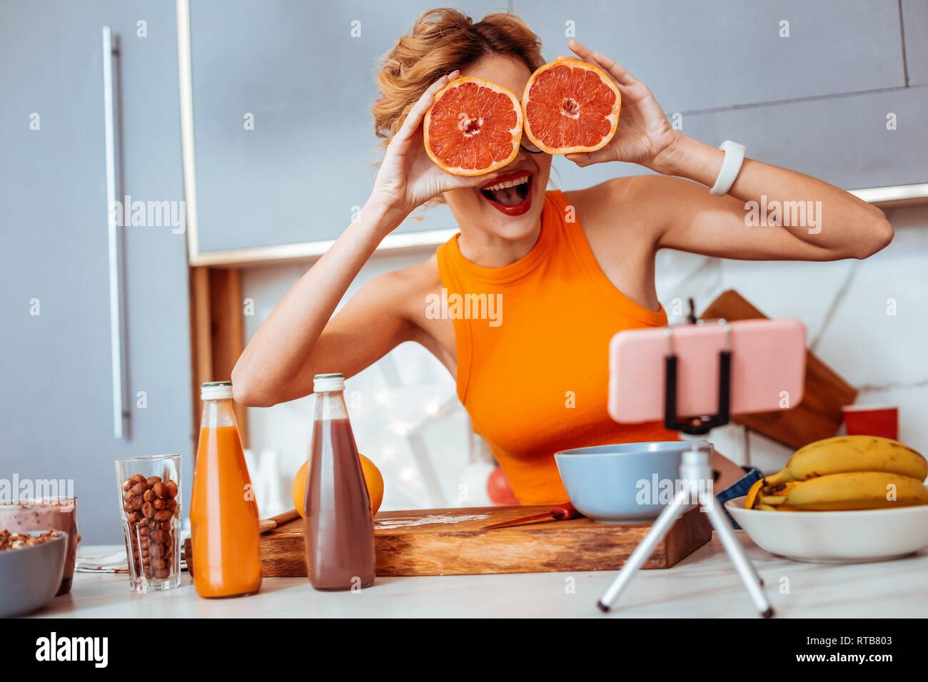 Happy delighted nice woman holding orange halves Stock Photo - Alamy
