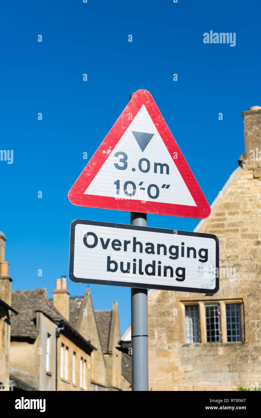 Sign warning of overhanging building in the pretty Cotswold market town ...